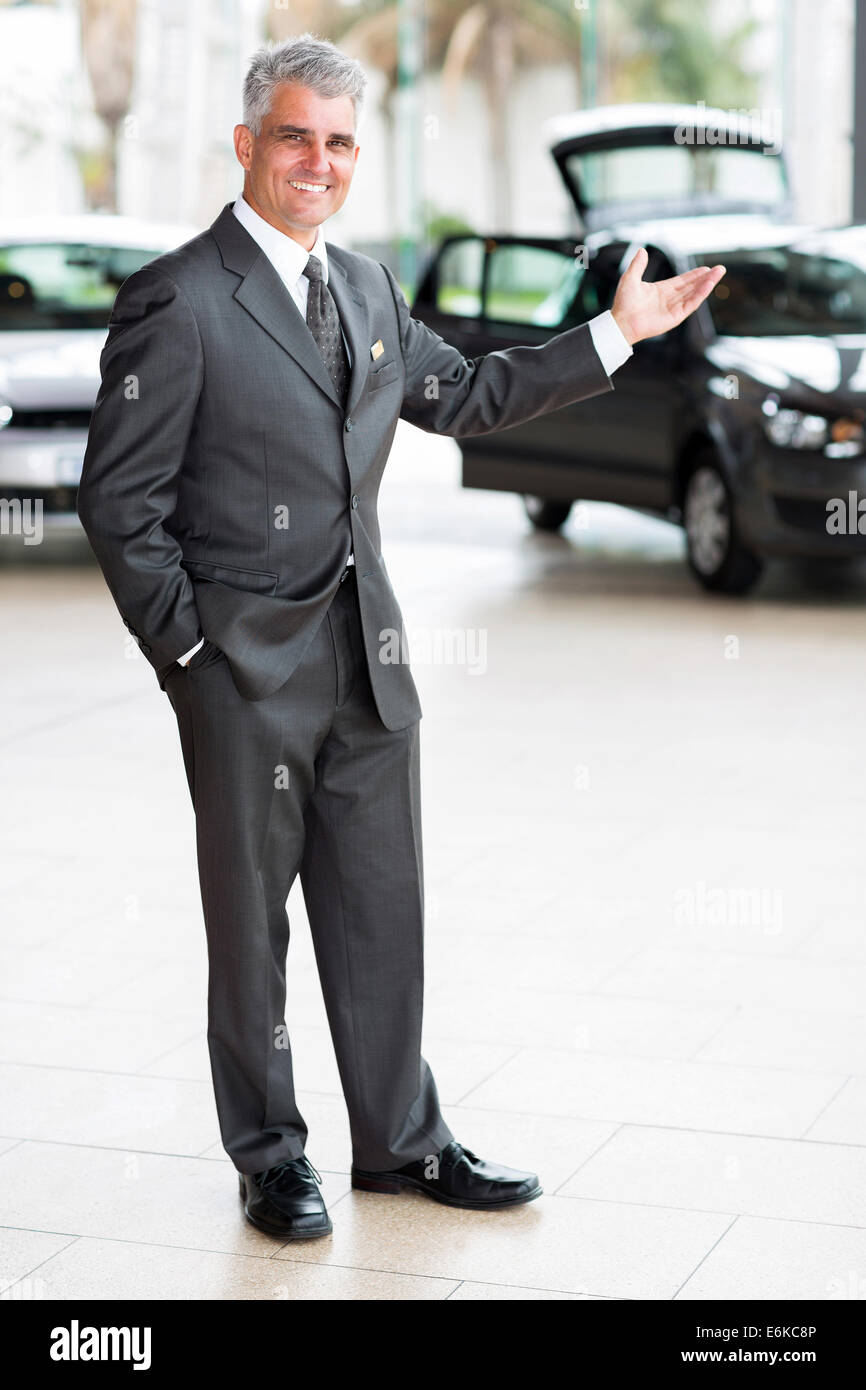 friendly car salesman doing welcoming gesture at car dealership Stock ...