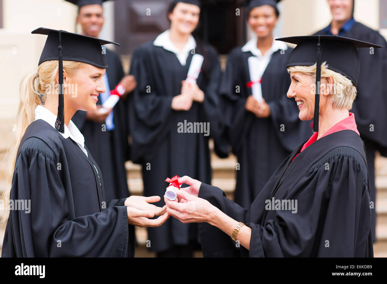 happy young female graduate receiving diploma from professor Stock ...