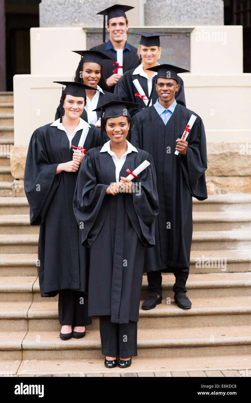group of happy young college graduates in front of school building ...