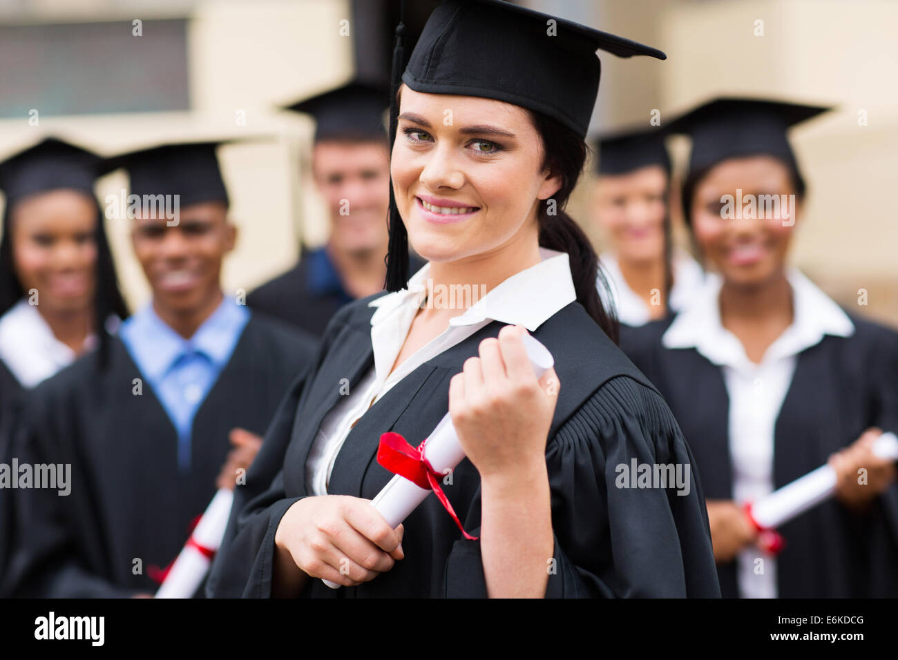 portrait of attractive female college graduate with classmates on ...