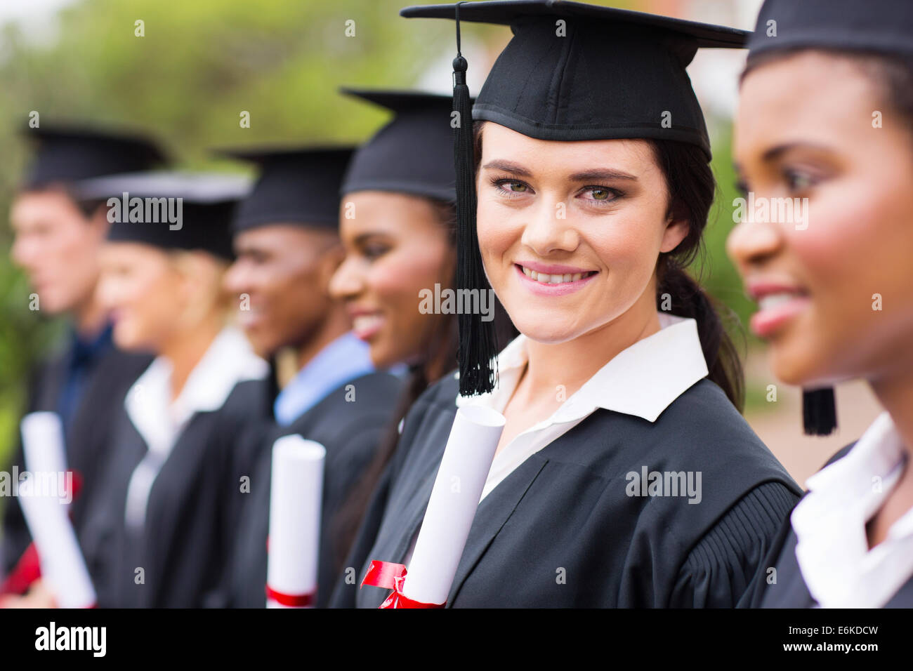 smiling female college graduate standing with friends at graduation ...