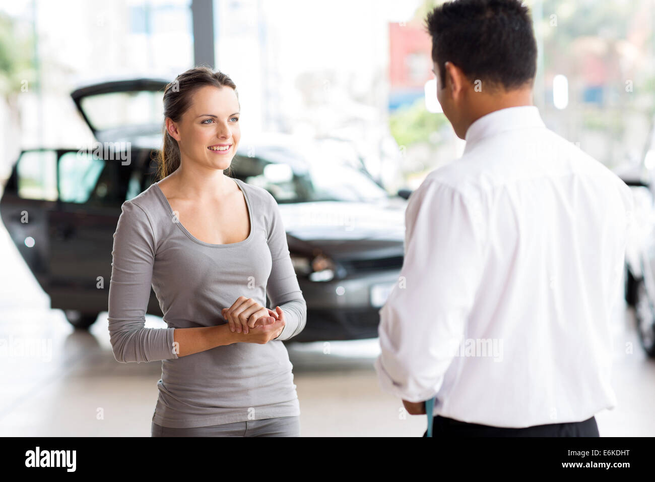 friendly car salesman talking to a young woman inside showroom Stock ...