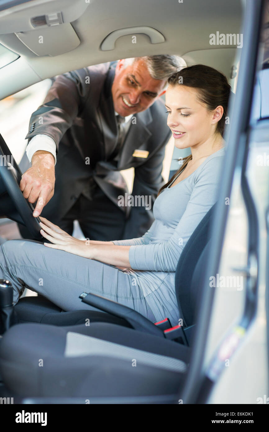 middle aged car salesman showing car features to young customer Stock ...