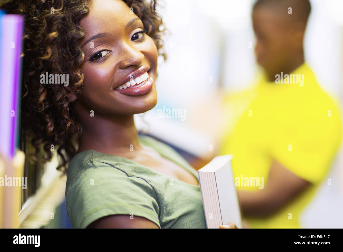 pretty female African uni student holding a book in library Stock Photo ...