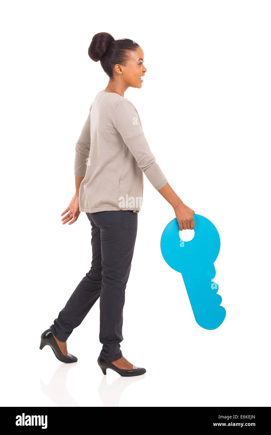 side view of young African woman walking with a huge toy key Stock ...