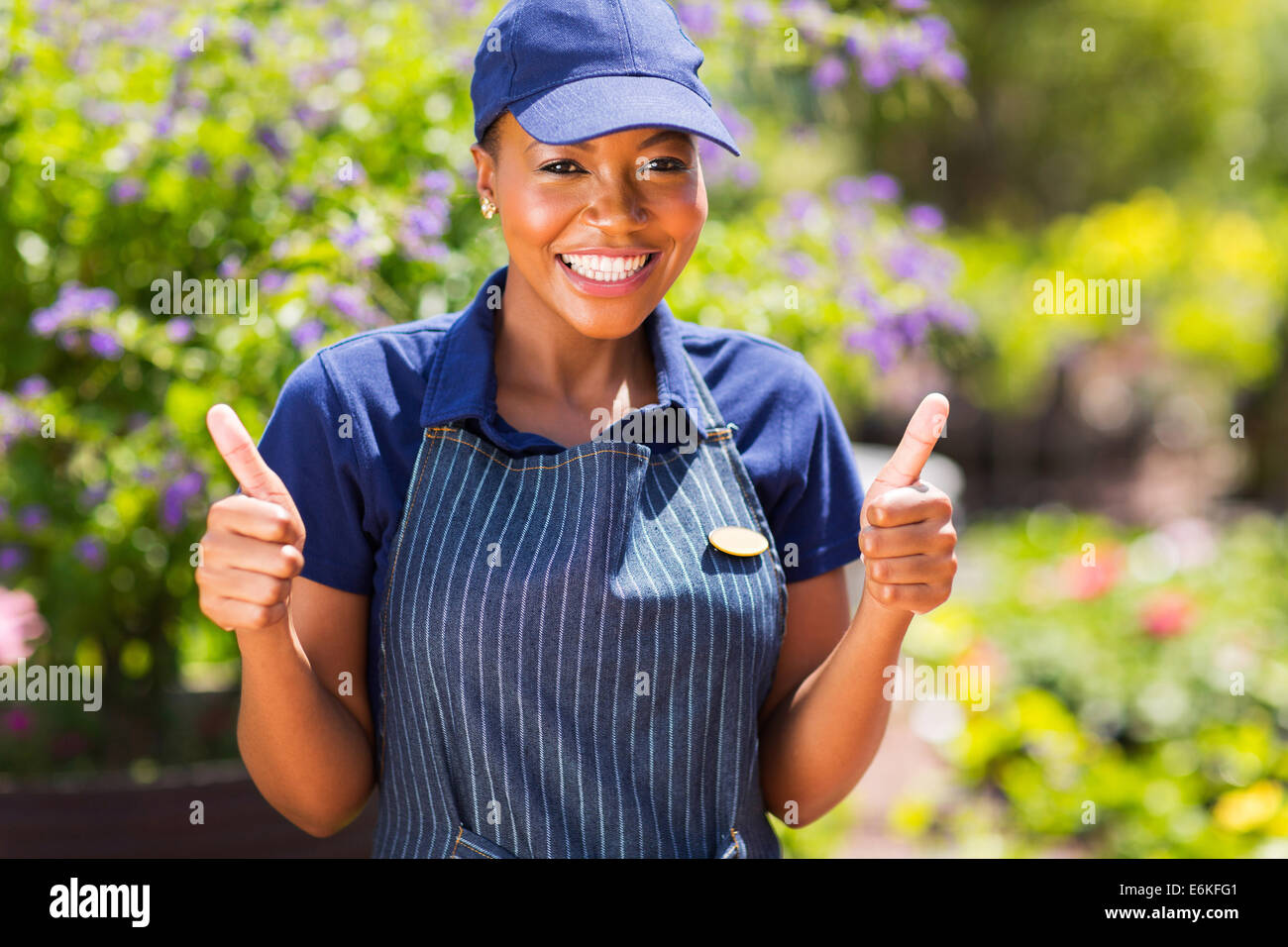 cheerful African female nursery worker with thumbs up Stock Photo - Alamy
