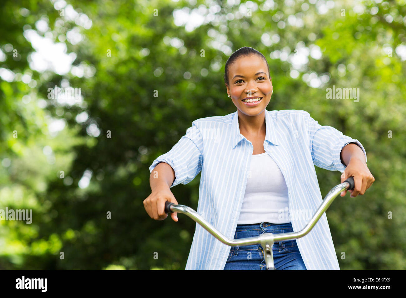 pretty young African American woman riding a bike in forest Stock Photo ...