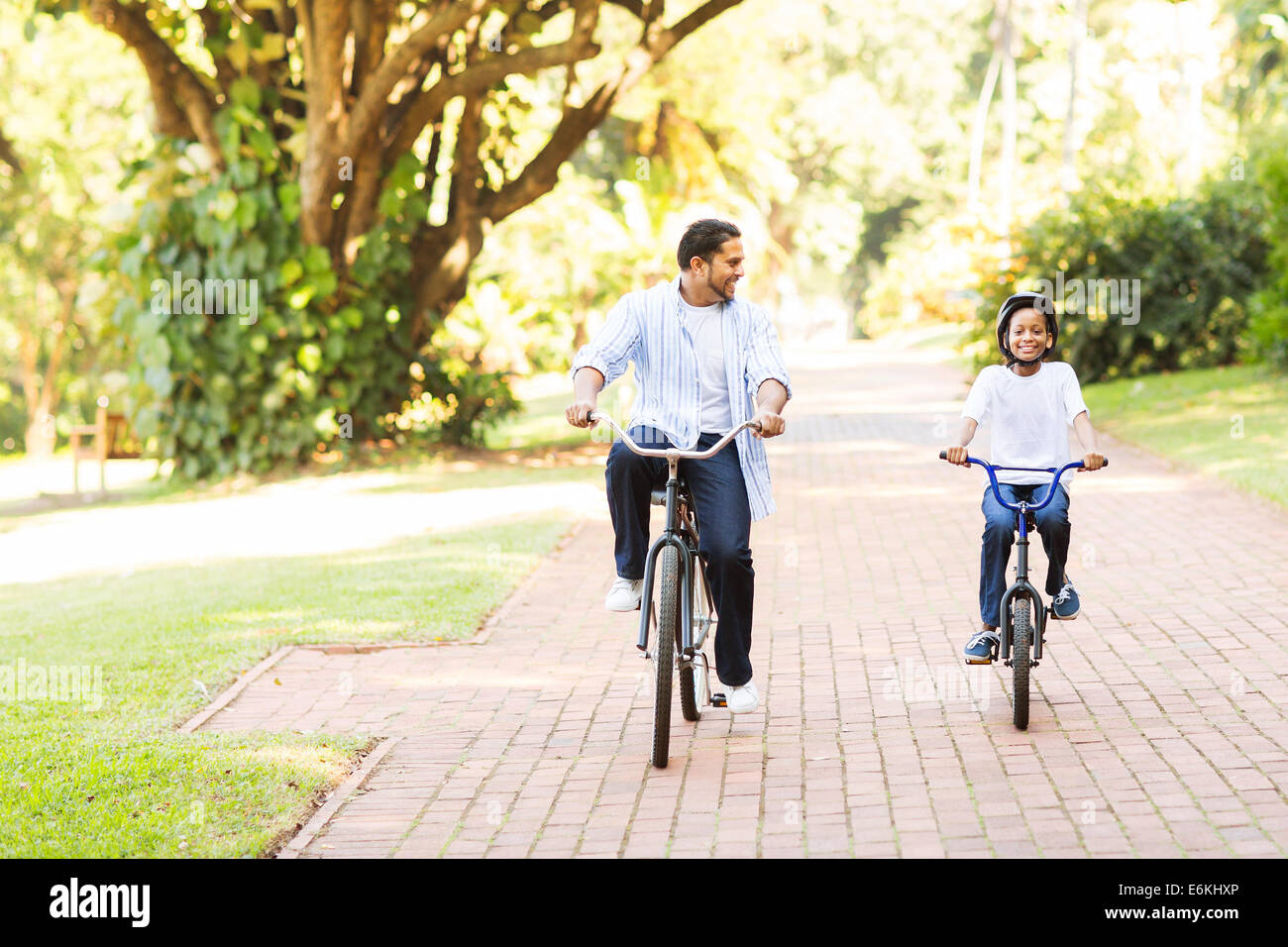 cheerful Indian father and daughter riding bikes in the park Stock ...