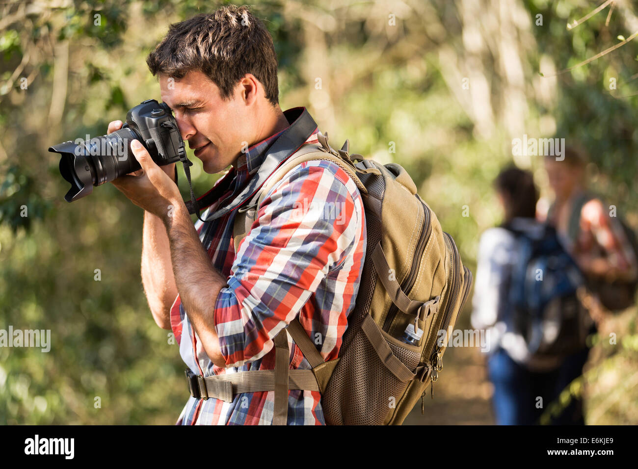 young man taking photos with dslr camera during hiking with friends ...