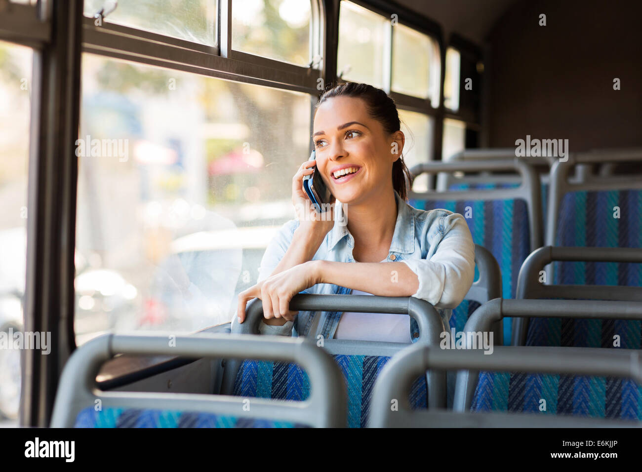beautiful female commuter talking on cell phone while taking bus to ...