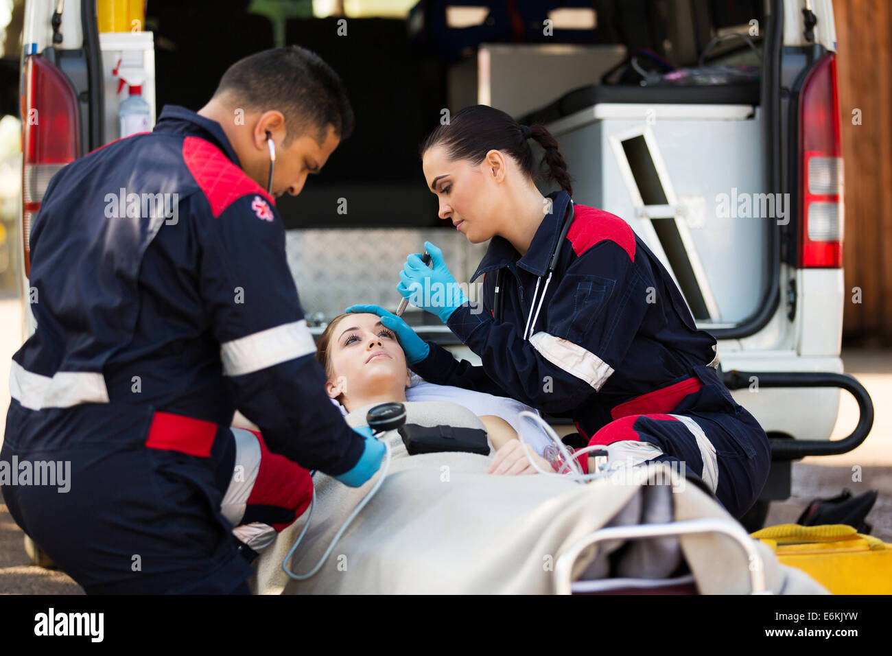 paramedic team examining young female patient Stock Photo - Alamy