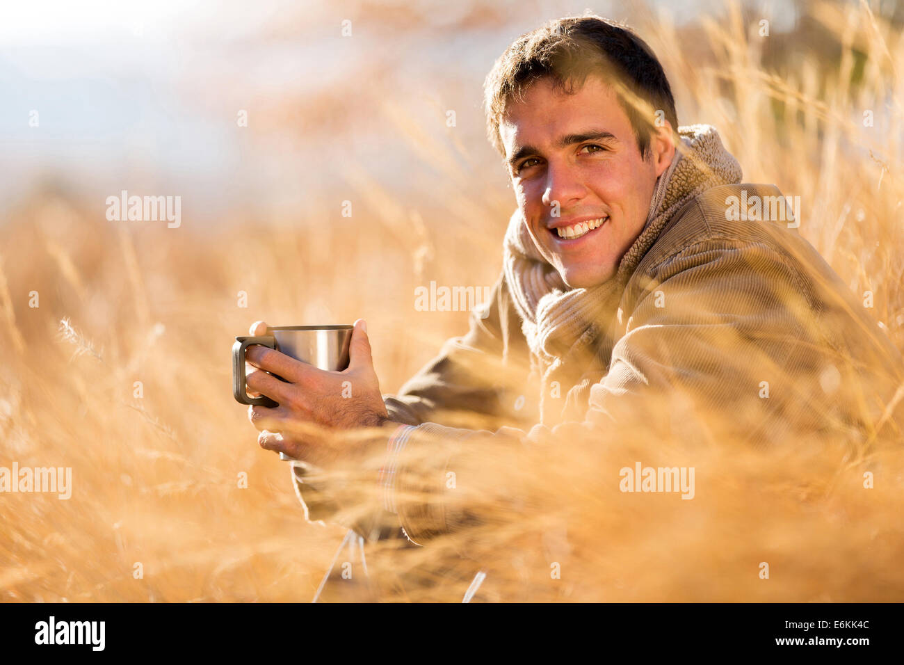 cheerful young man drinking coffee outdoors in fall Stock Photo - Alamy