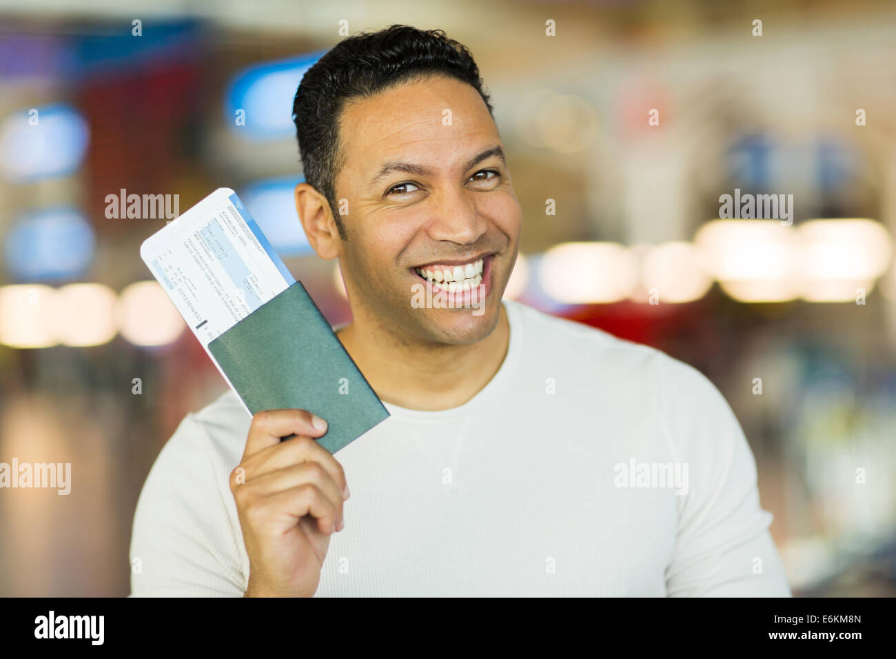 cheerful mid age man holding passport and boarding pass at airport ...