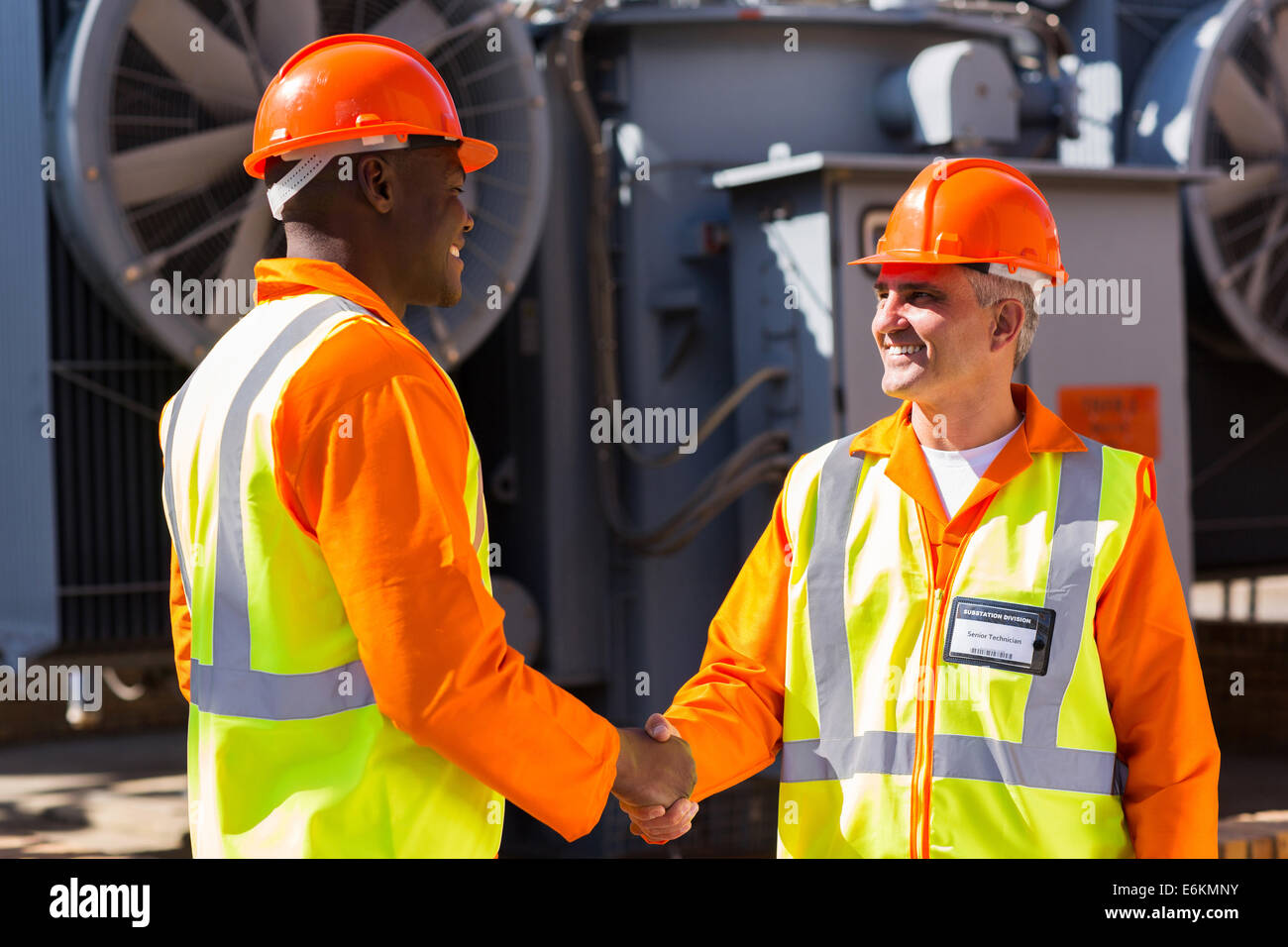 friendly power company co-workers hand shaking in electrical substation ...