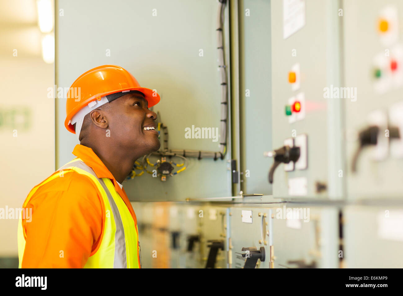 smiling young African American electrician looking at control room ...