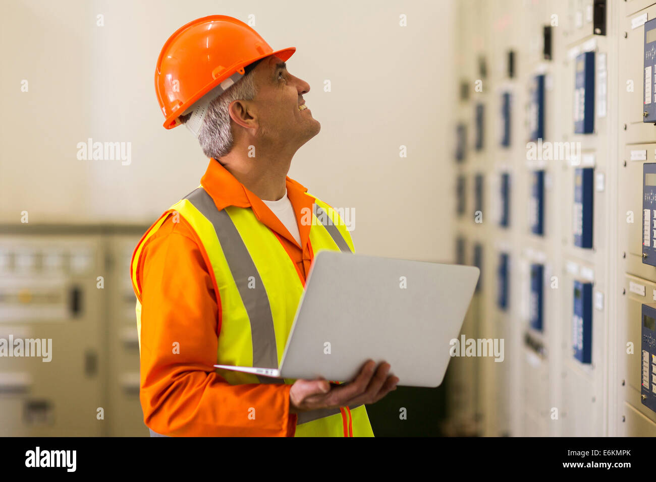 middle aged electrical engineer with laptop computer in control room ...