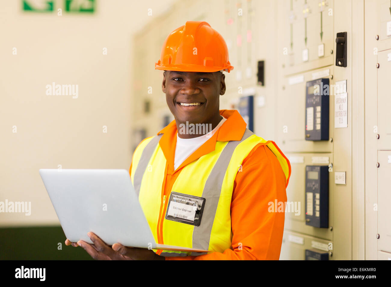 portrait of African engineer holding laptop in power plant control room ...