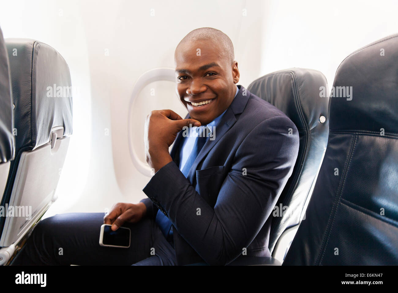 young African American businessman holding cell phone on airplane Stock ...