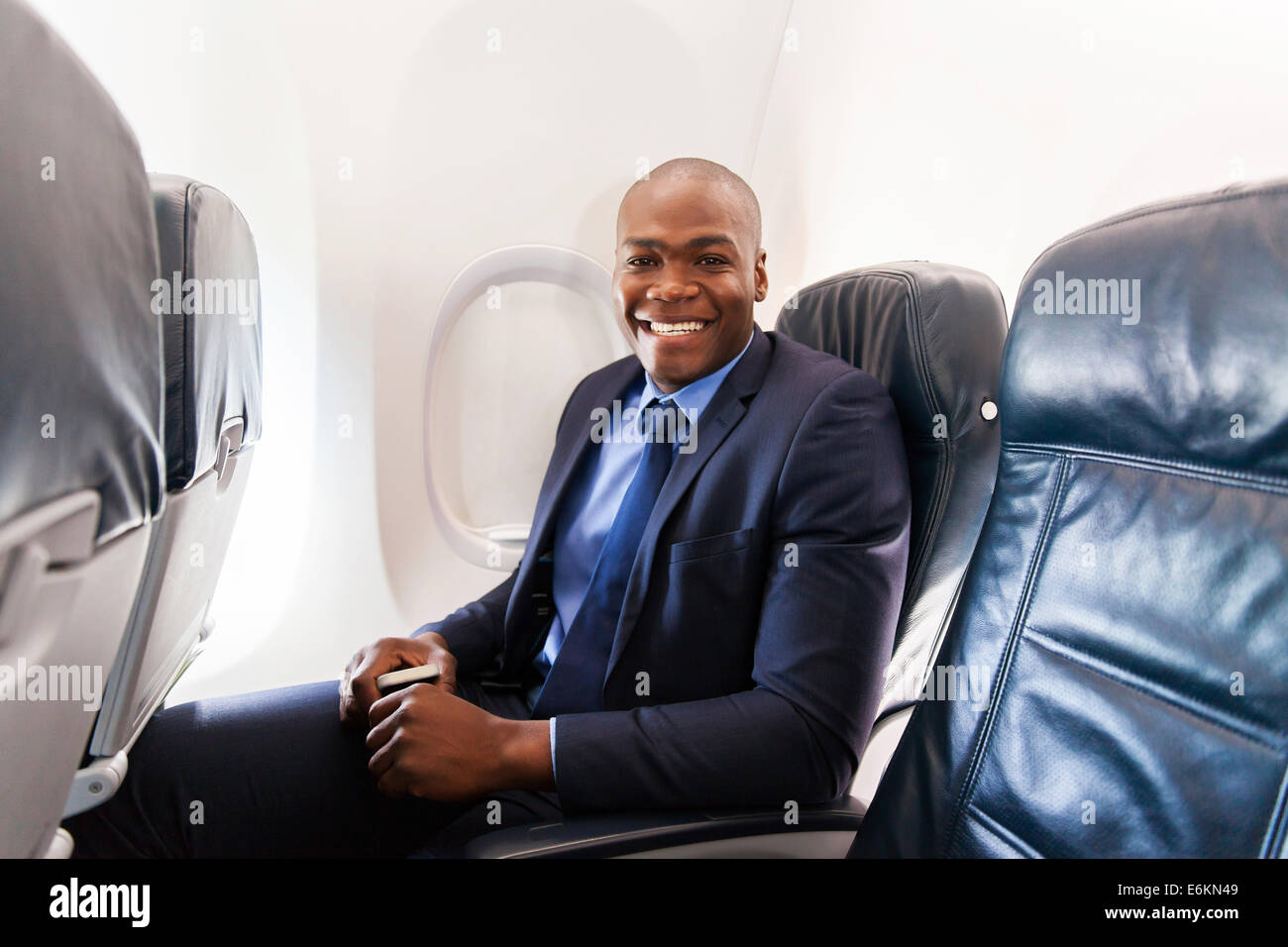 cheerful afro American businessman on board of an airplane during the ...