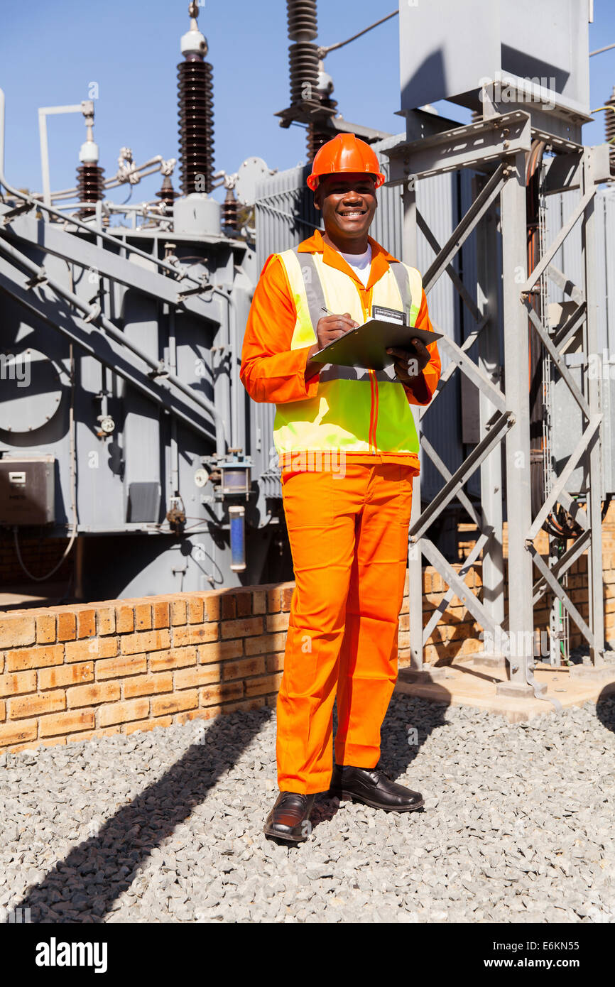 happy afro American electrical engineer with clipboard in power plant ...