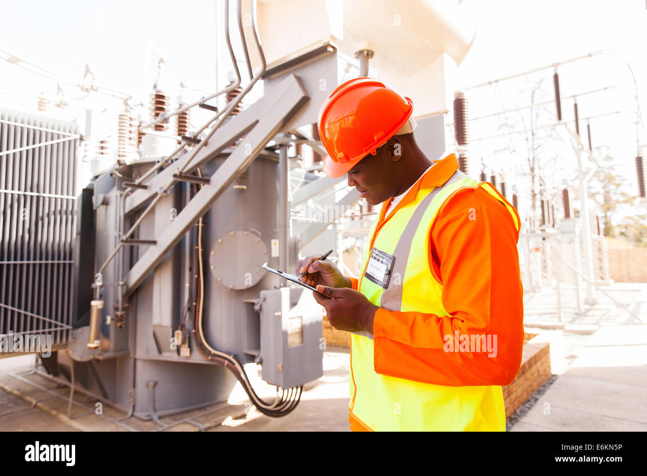 handsome afro American electrical engineer writing on clipboard in ...
