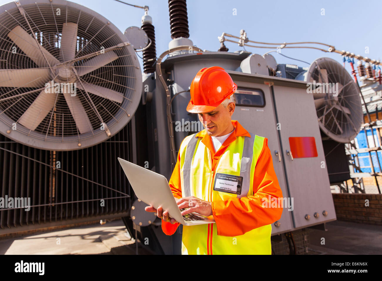 experienced senior electrical technician using laptop computer in front ...