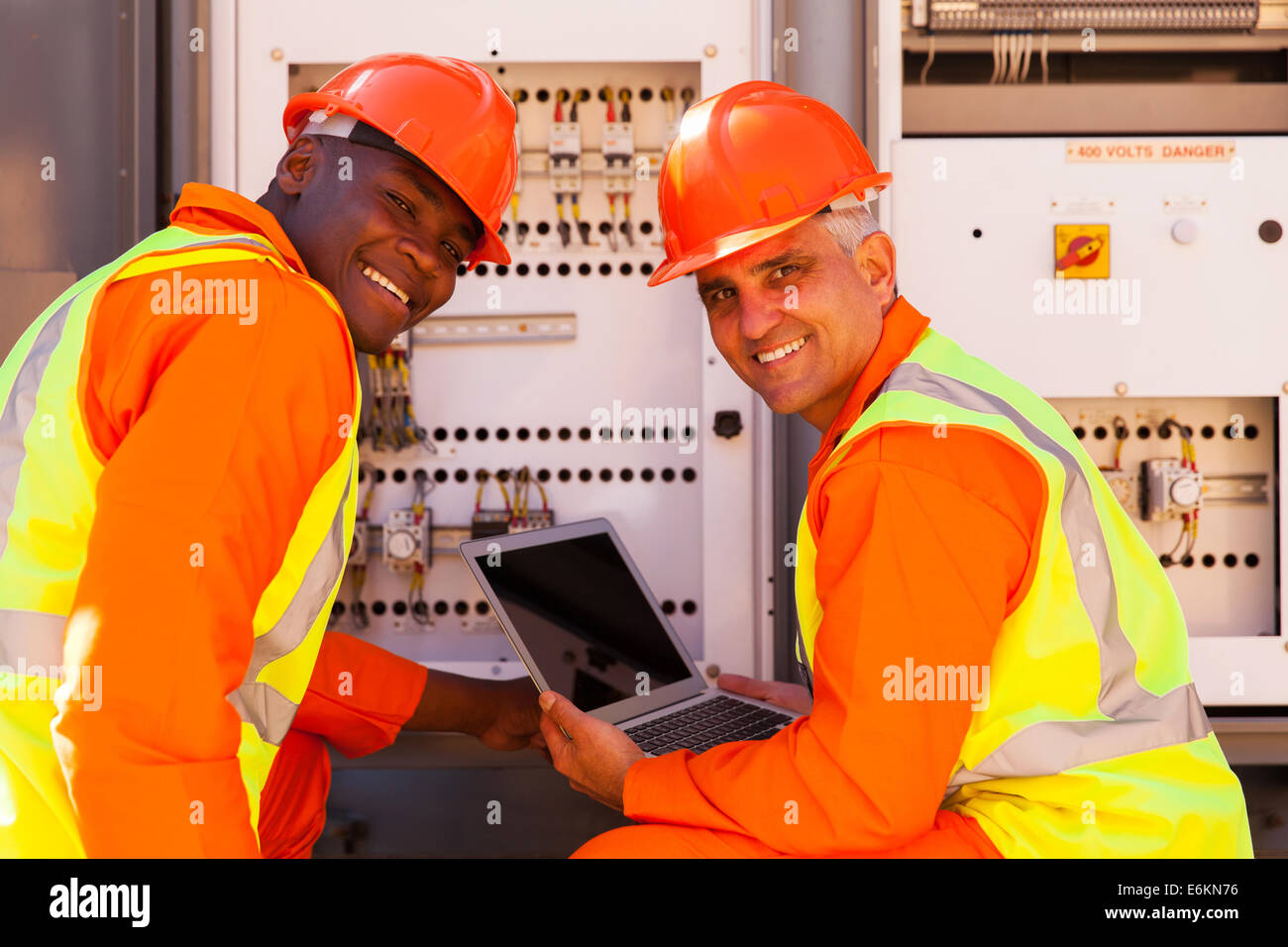 modern electrical co-workers using laptop computer checking transformer ...
