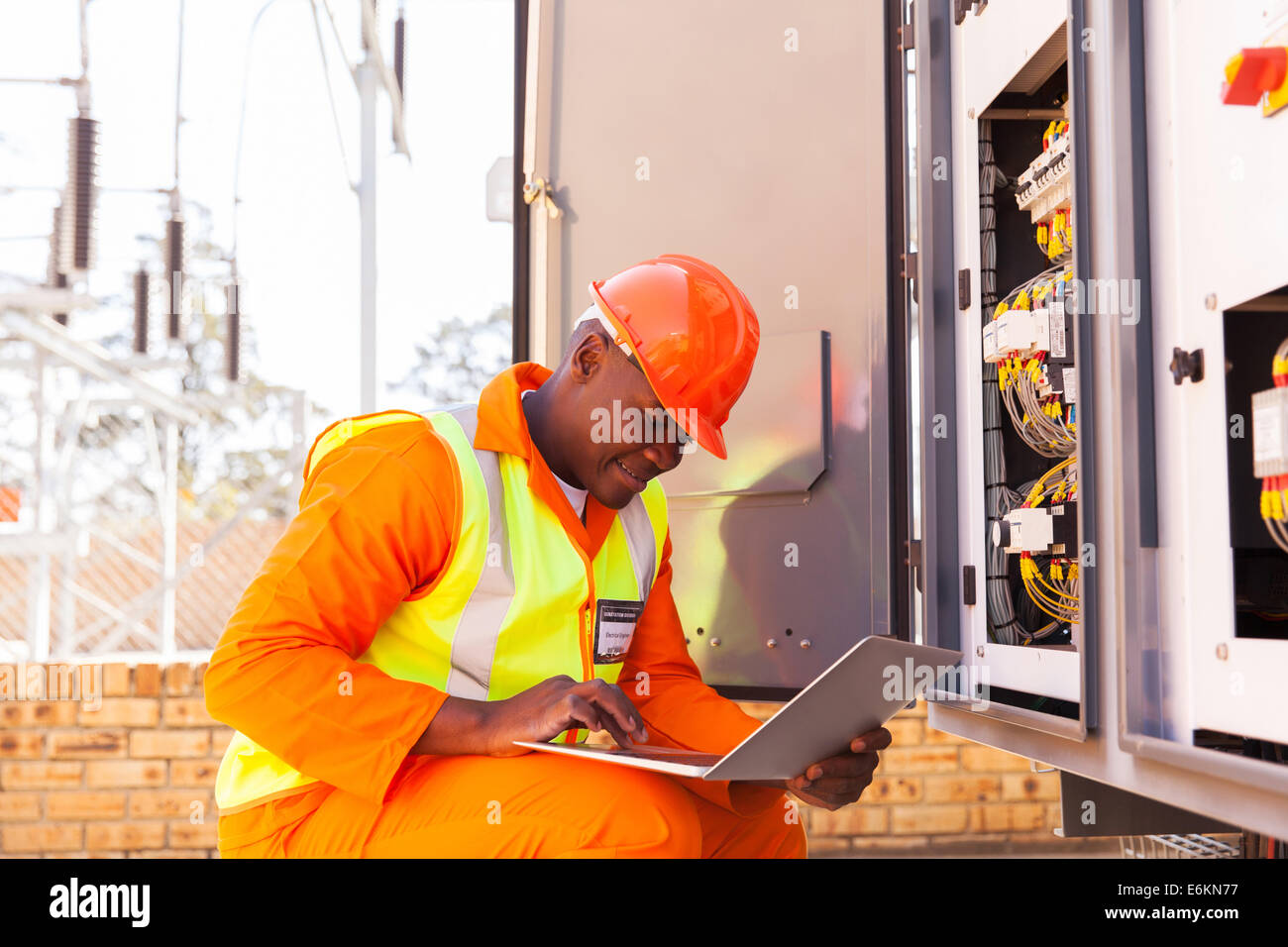 handsome African electrical engineer working on laptop next to ...