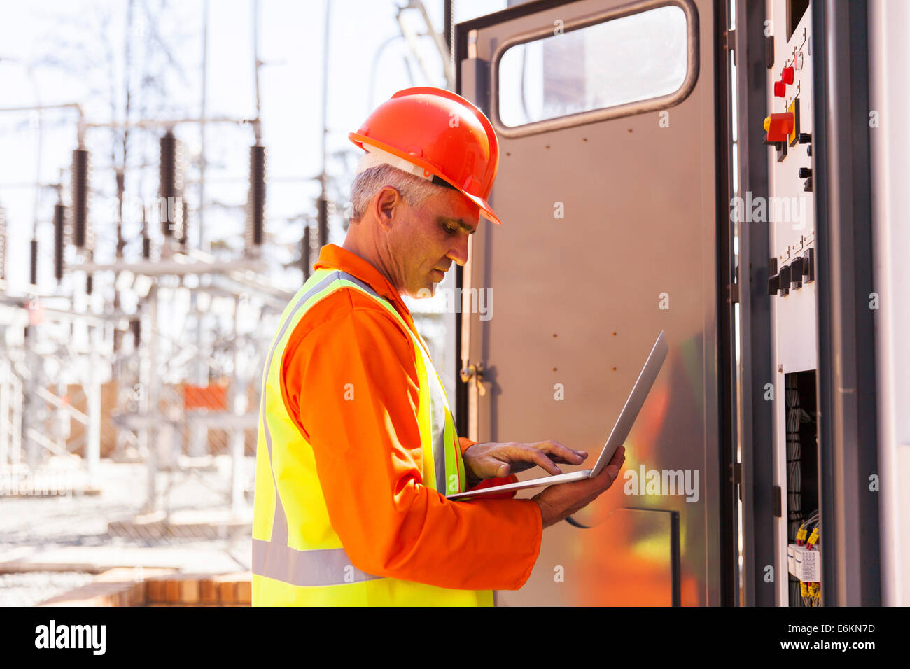 professional mature electrician working on laptop computer in ...