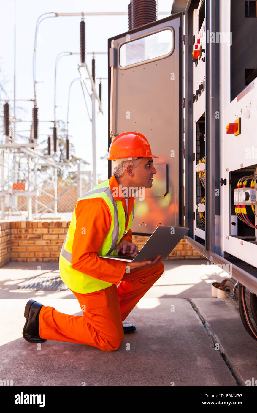 senior technician checking computerized transformer status with laptop ...