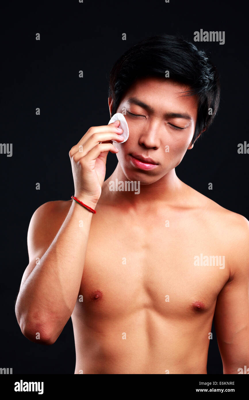 Asian man wipes his face with cotton pad on black background Stock ...