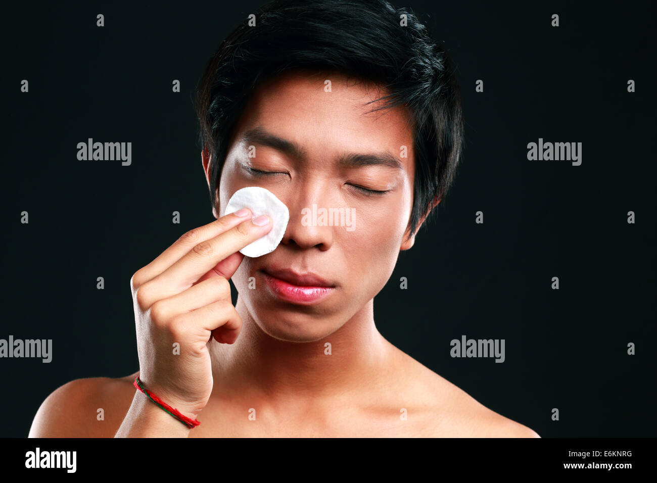 Asian man wipes his face with cotton pad on black background Stock ...