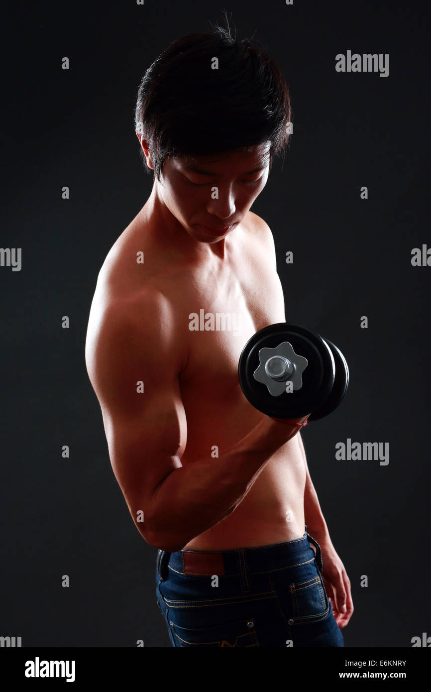 Asian man working out with dumbbell on black background Stock Photo - Alamy