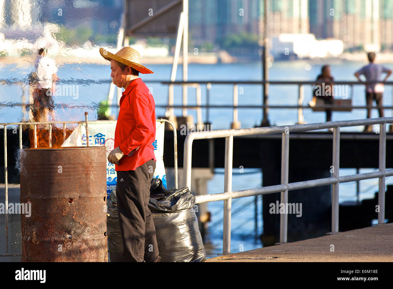 The Burning Barrel. Chinese Man In A Straw Hat During Waste In An Oil ...
