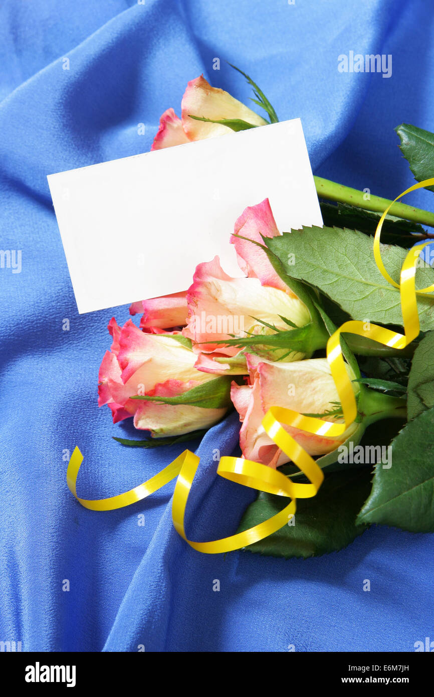 Roses over blue silk background with blank visiting card for your own ...