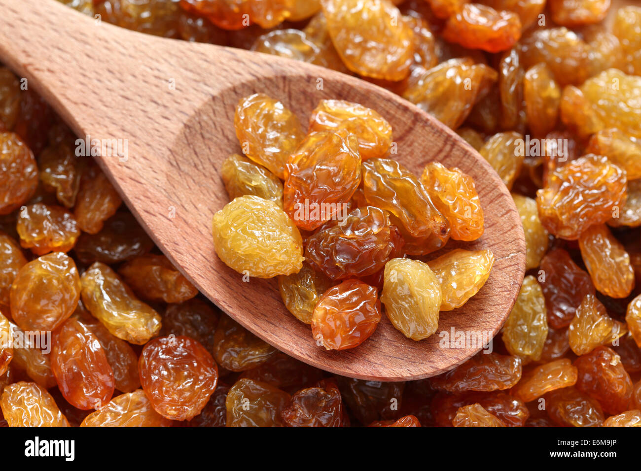 Raisins in a wooden spoon on raisins background. Closeup Stock Photo ...