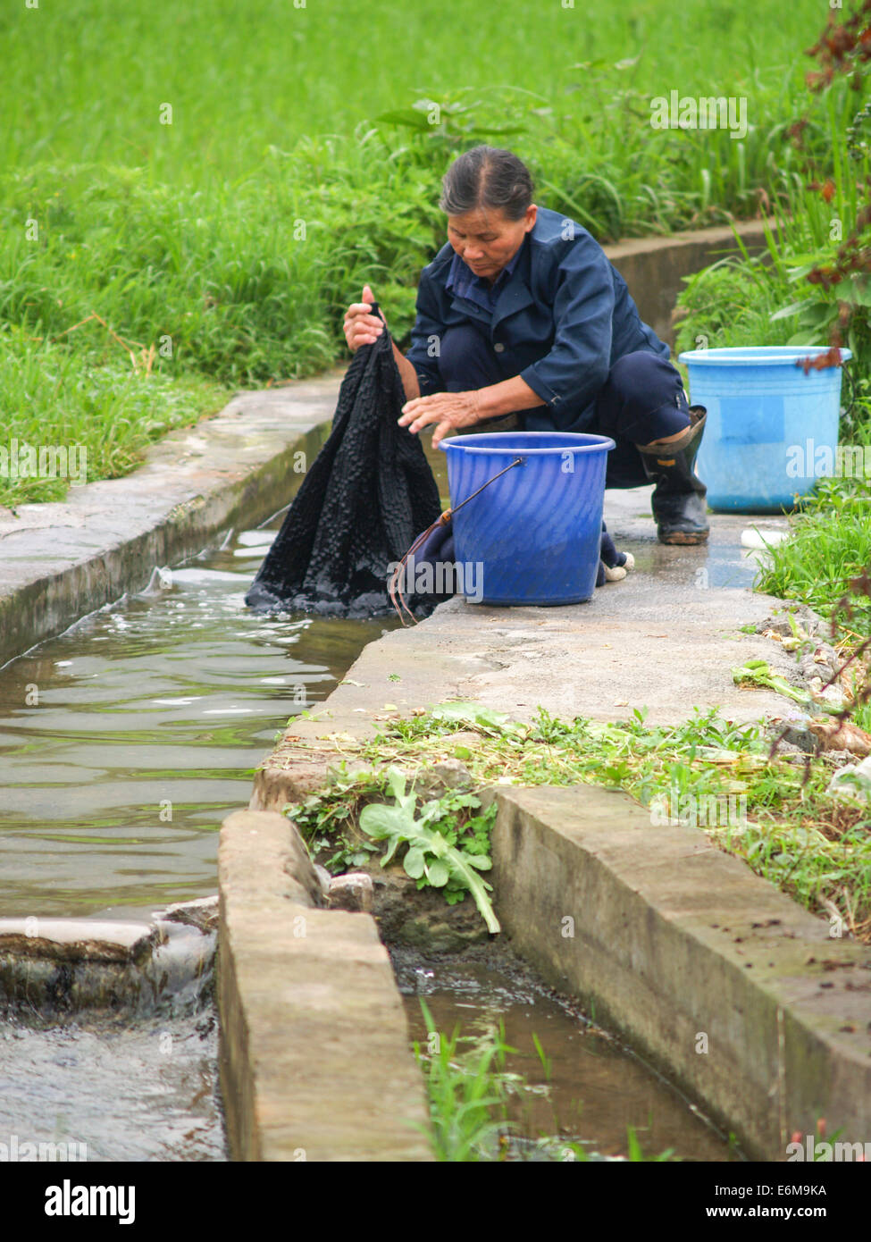 A local woman washes clothes in a stream, farmland limestone peaks in ...