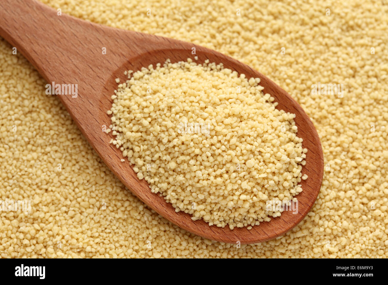 Couscous in a wooden spoon on couscous background Stock Photo - Alamy