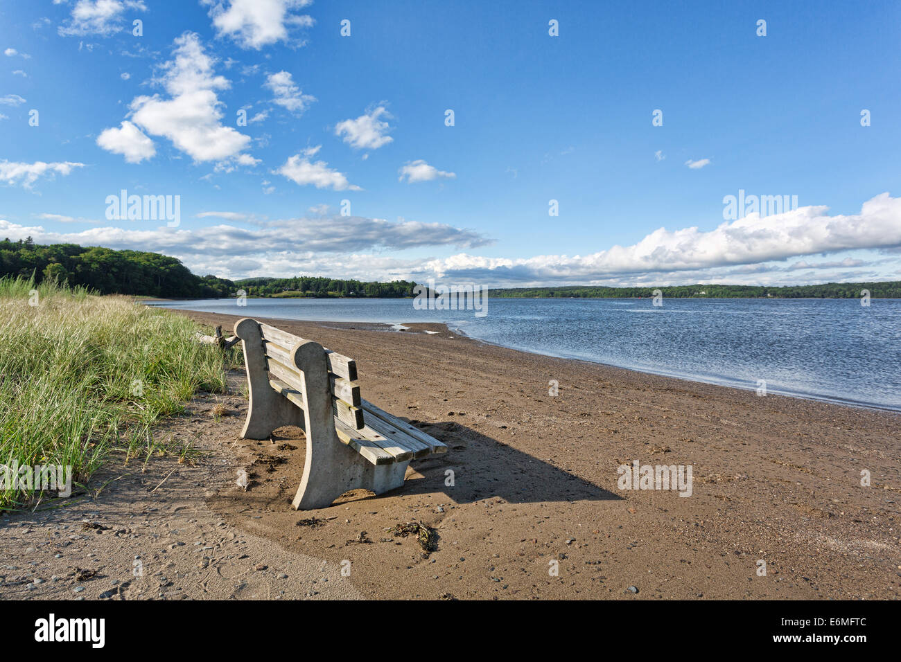 An old concrete and wood bench at Sandy Point Beach facing the ...