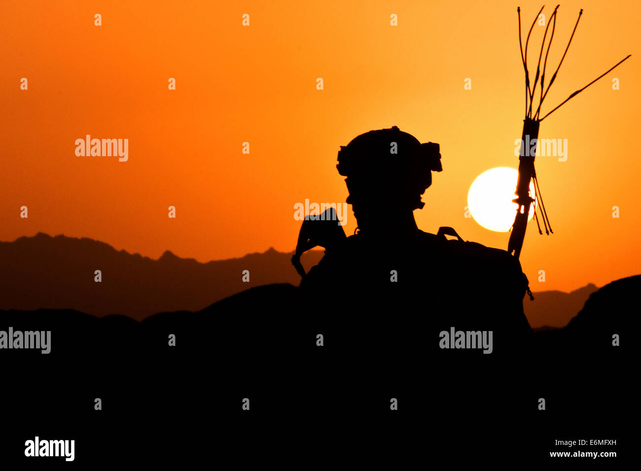 A US Army soldier is silhouetted by the setting sun while on combat ...