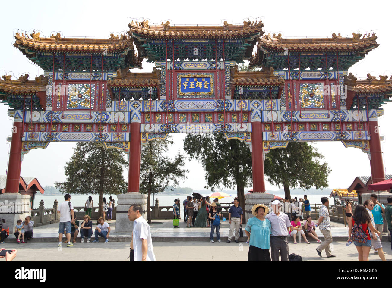 Tourists pose in front of a paifang, a gate based on traditional ...