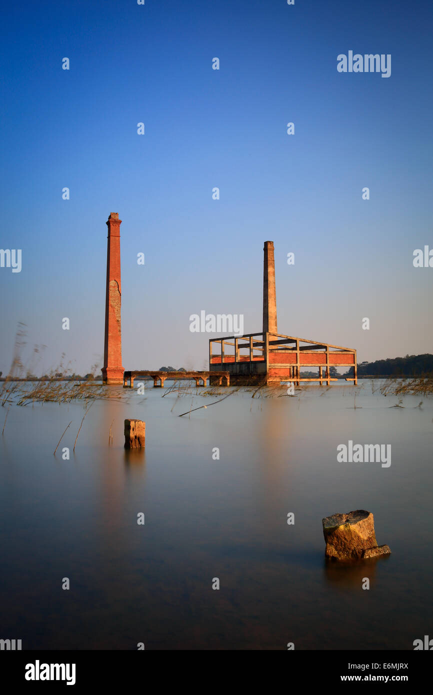 Old decaying factory building with reflections in lake. Old factory on ...