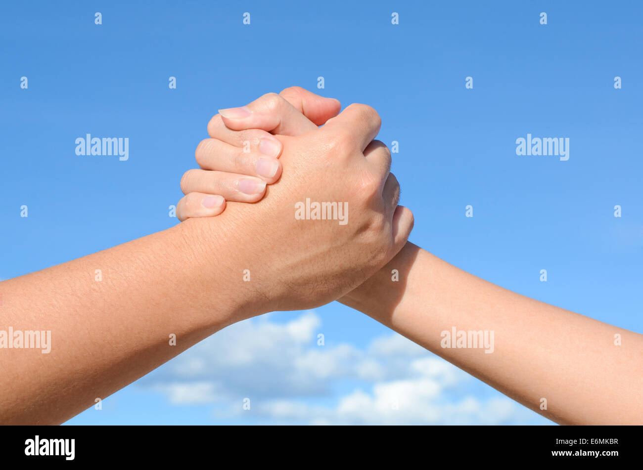 Partner hand between a man and a woman on blue sky background, Teamwork ...