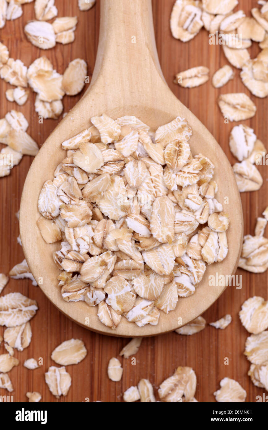 Rolled oats (oat flakes) in a wooden spoon. Closeup Stock Photo - Alamy