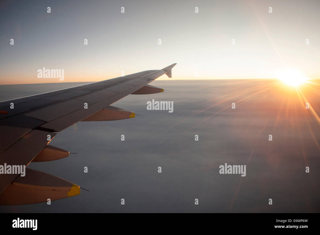 Sunrise from an airplane above the clouds with wing unit, above Norway ...