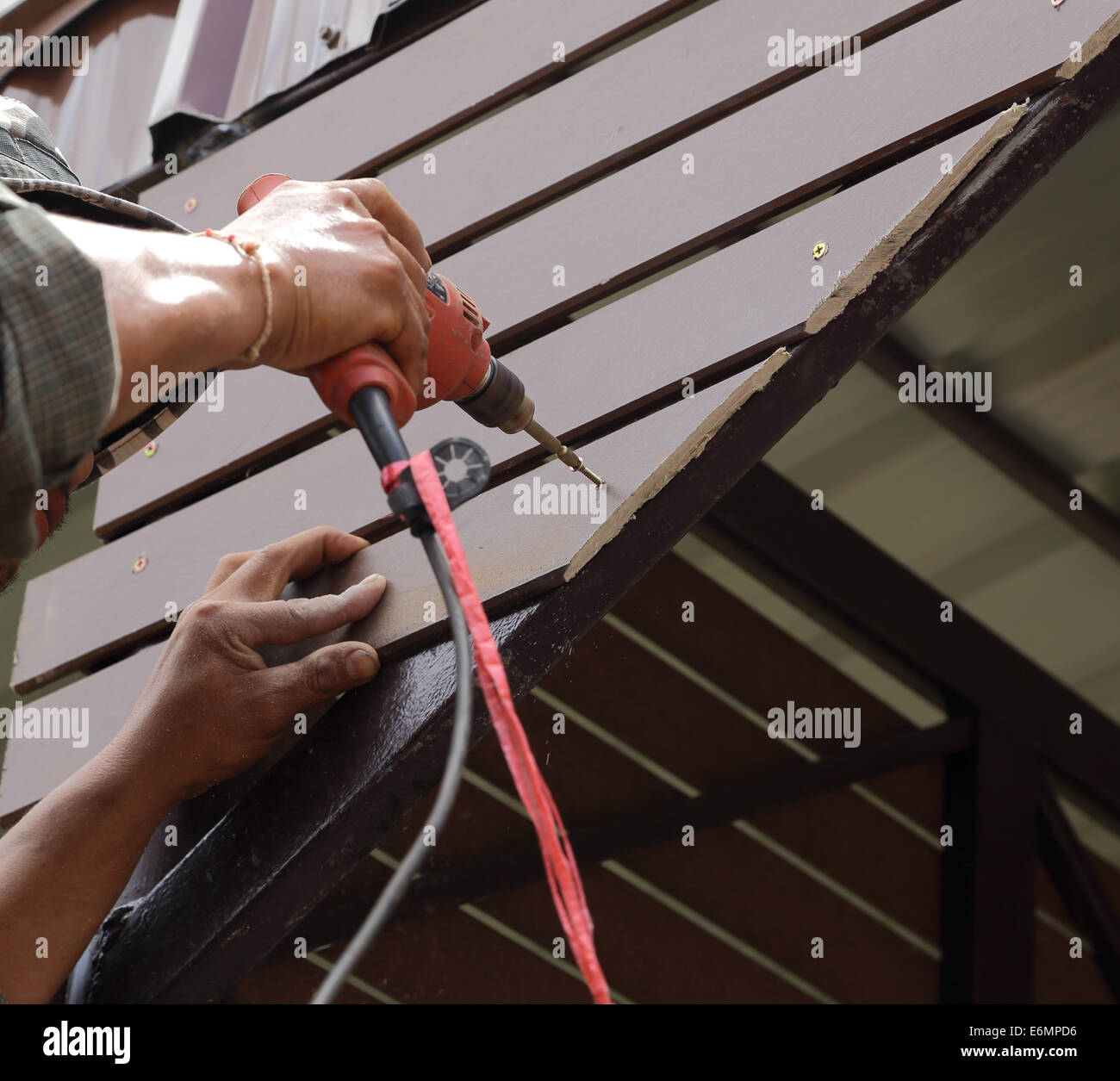 carpenter at lock installation with electric drill into construction ...