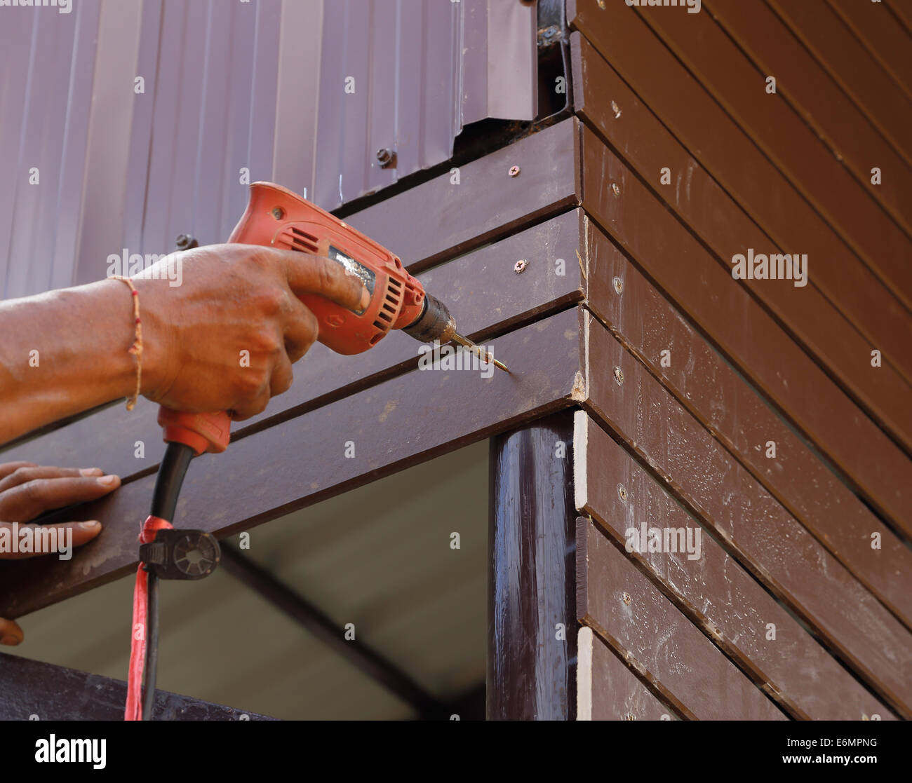 carpenter at lock installation with electric drill into construction ...