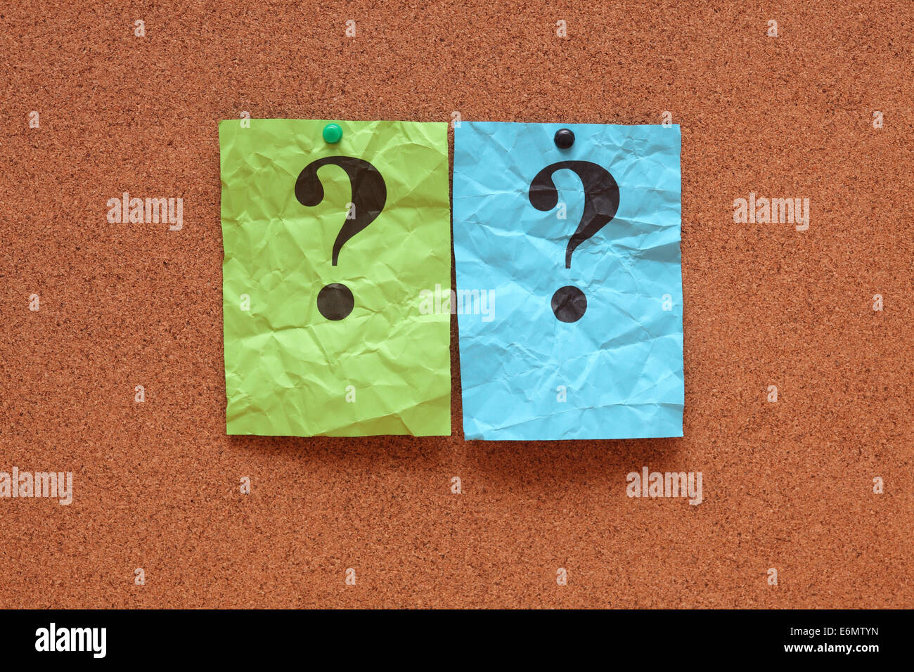 Crumpled colorful paper notes with question marks on cork board ...