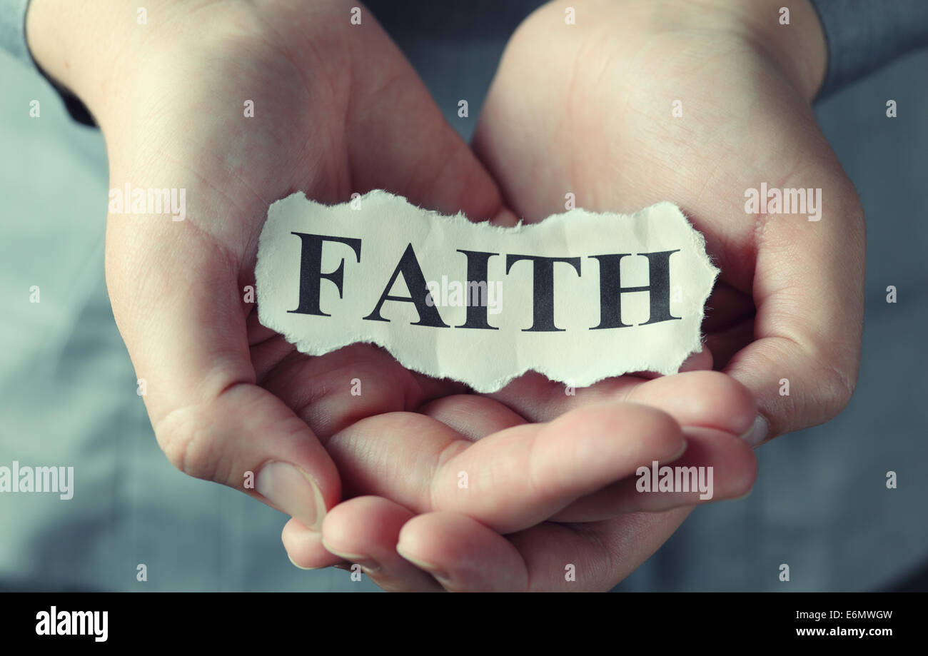 Torn piece of paper with the word "Faith" in the woman's palms. Cross ...