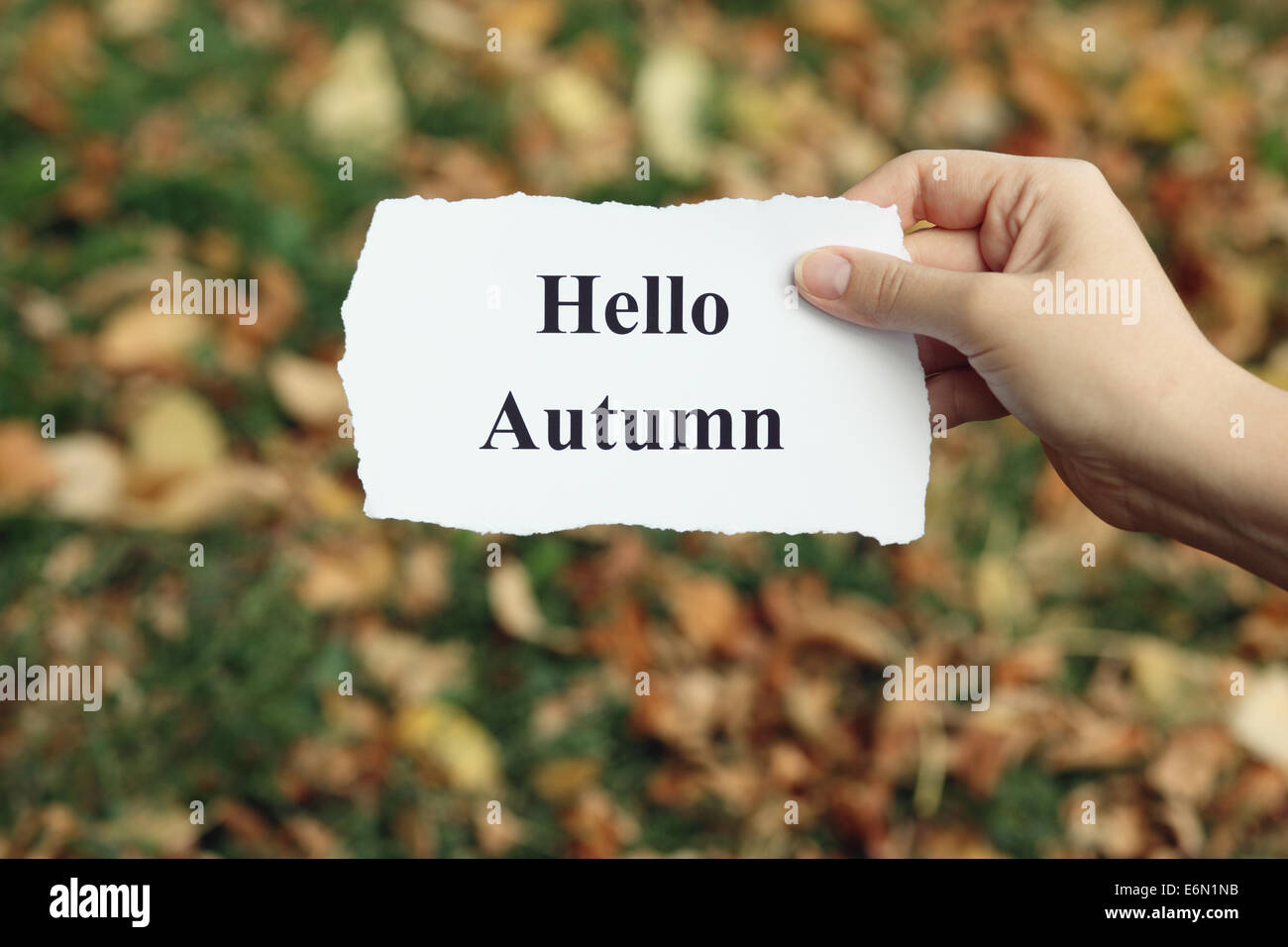 Torn piece of paper with the words saying "Hello Autumn" in the woman's ...